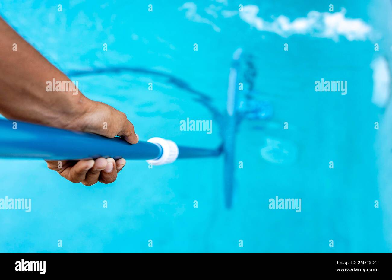 People cleaning swimming pool with suction hose. Close-up of man ...