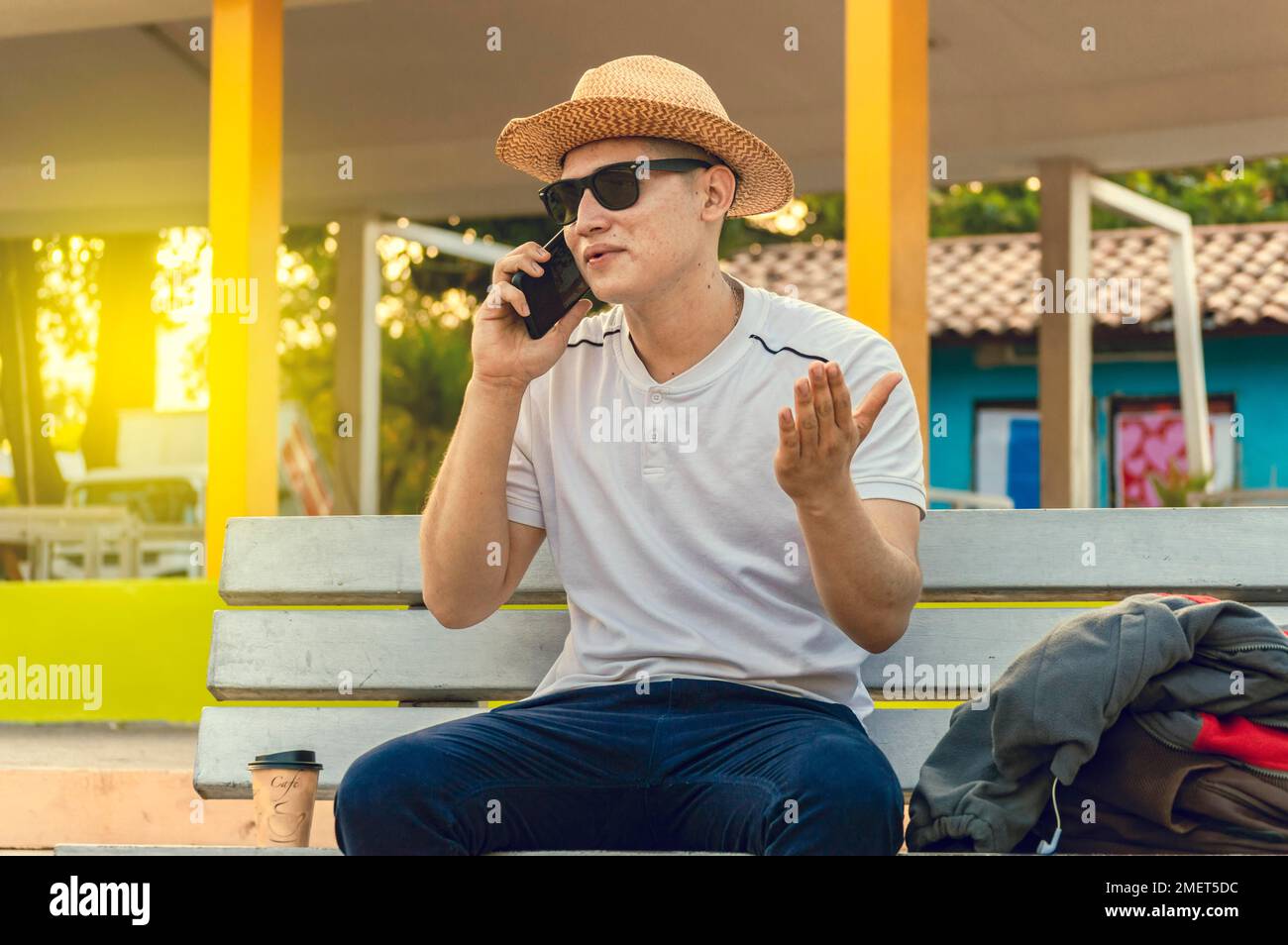 An attractive guy calling on a cell phone on a bench, a man sitting on ...