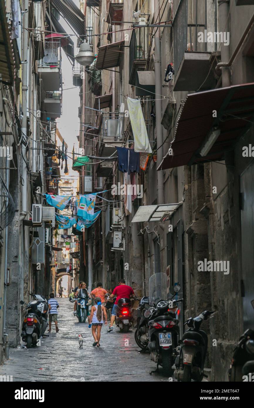 People walking down narrow alleys lined with buildings in summer ...