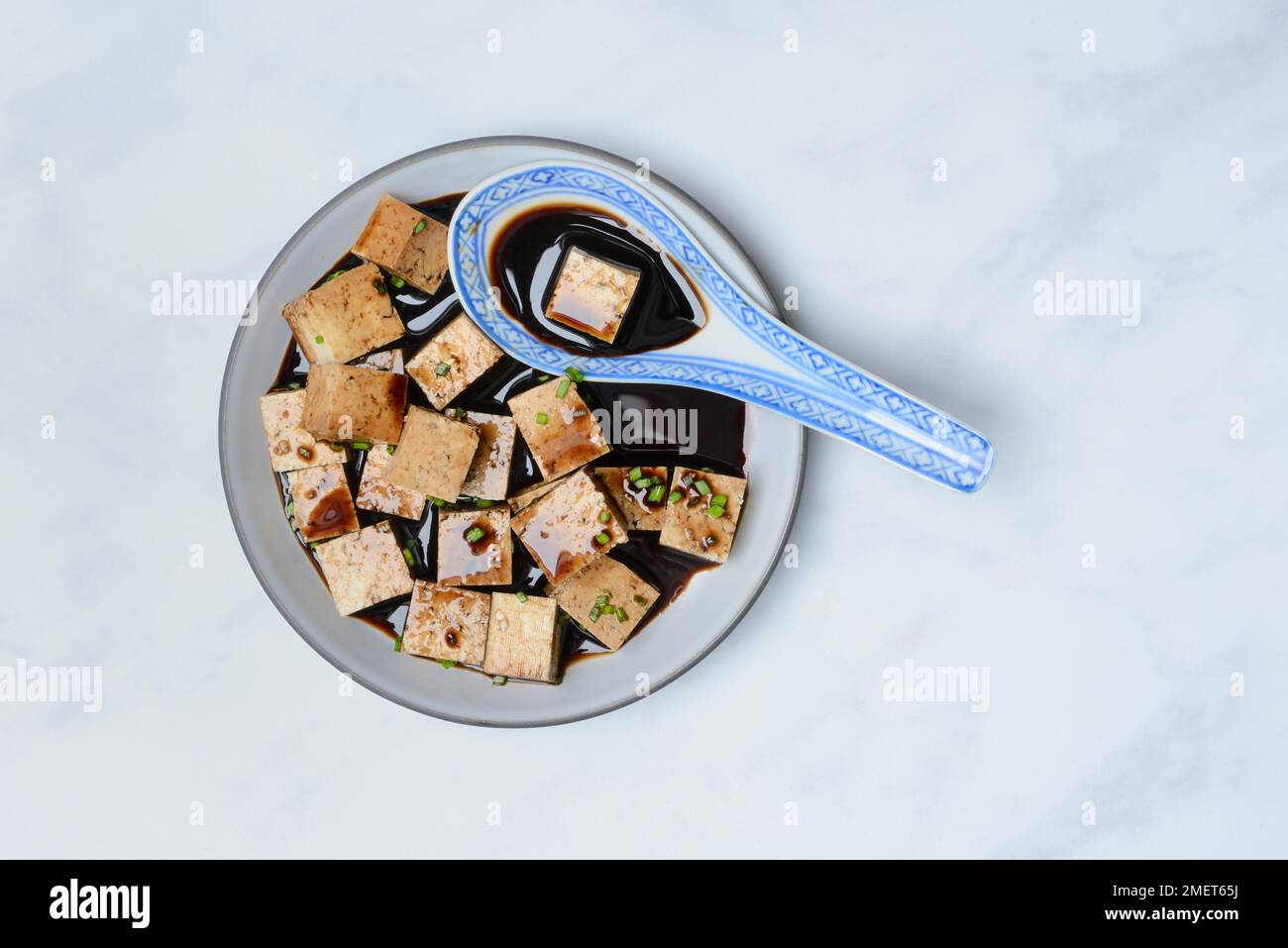 Soy sauce marinated tofu cubes in bowl with Asian ceramic spoon Stock ...