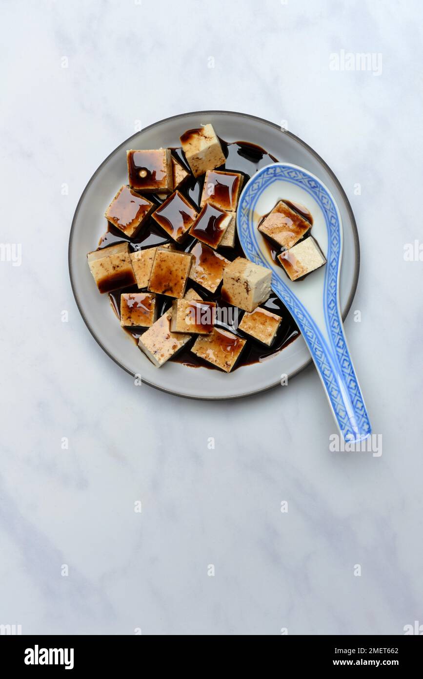 Soy sauce marinated tofu cubes in bowl with Asian ceramic spoon Stock ...