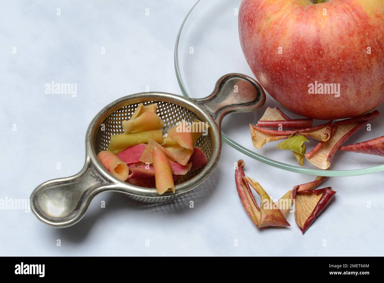Apple peel tea in tea strainer and apple, tea Stock Photo - Alamy