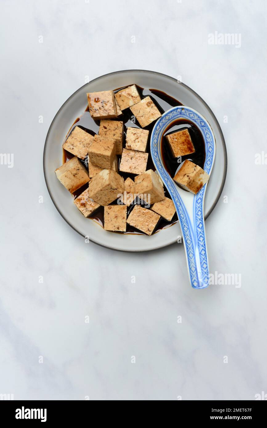 Soy sauce marinated tofu cubes in bowl with Asian ceramic spoon Stock ...