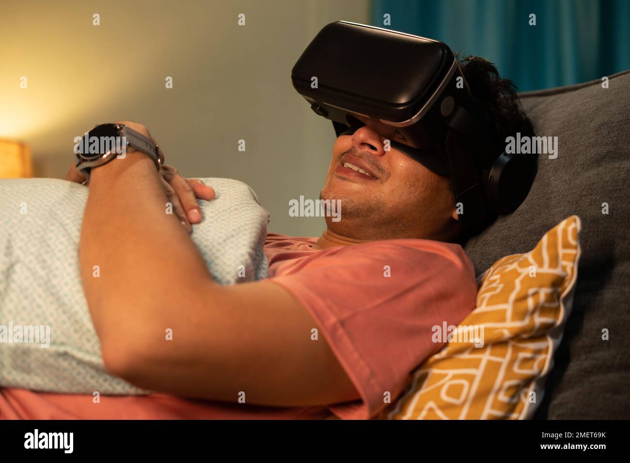 Smiling young man with VR or virtual reality headset experiencing ...