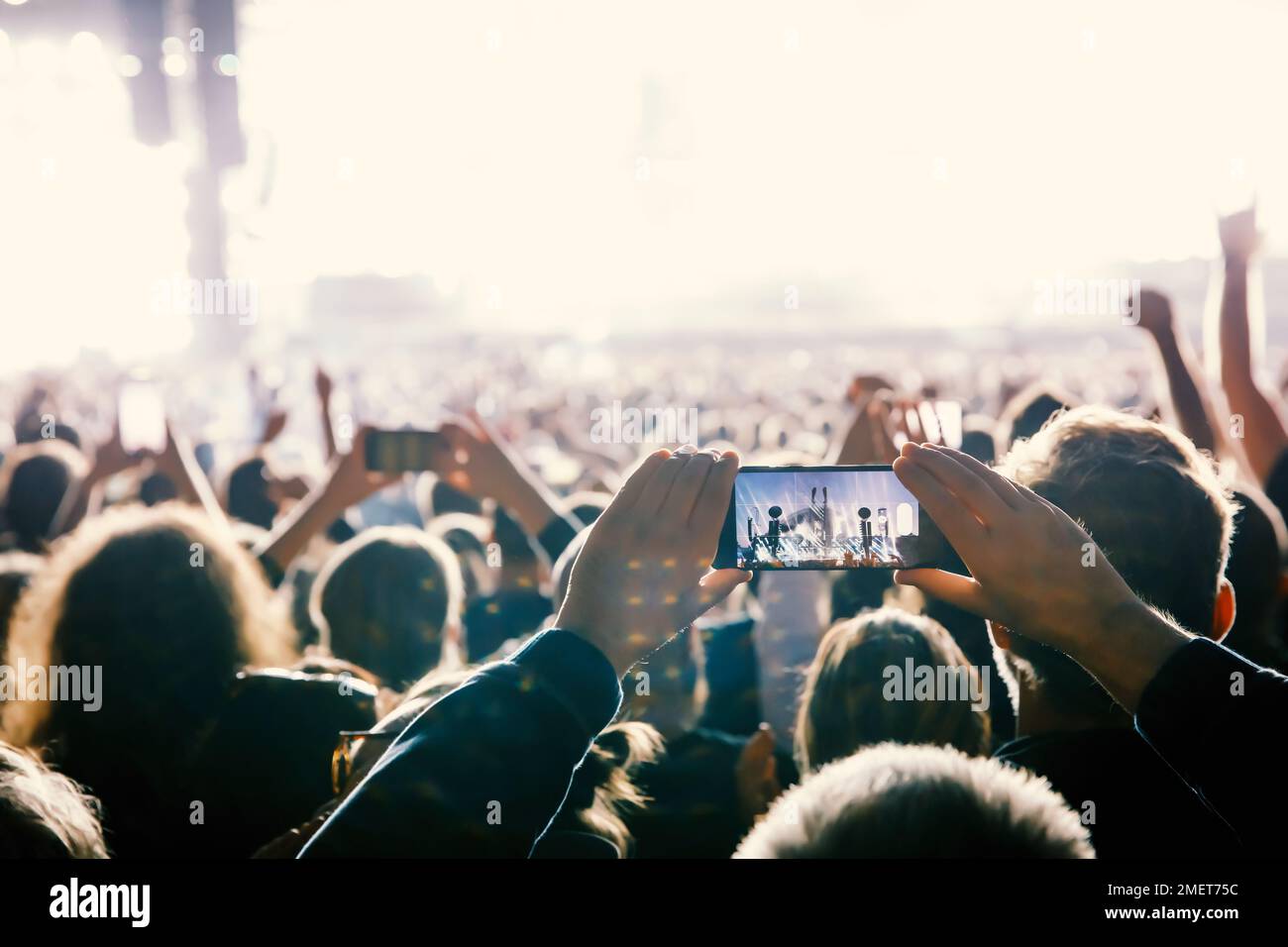 Making video of concert using a smartphone. Cheering people on an ...