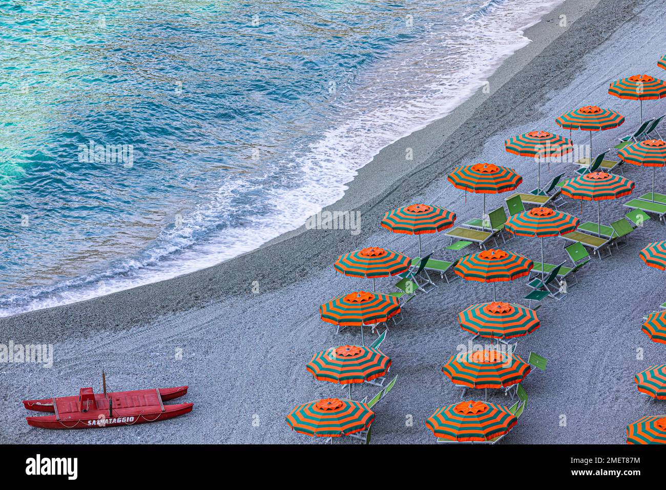 Sun loungers, parasols and red lifeboat on the beach di Fegina ...