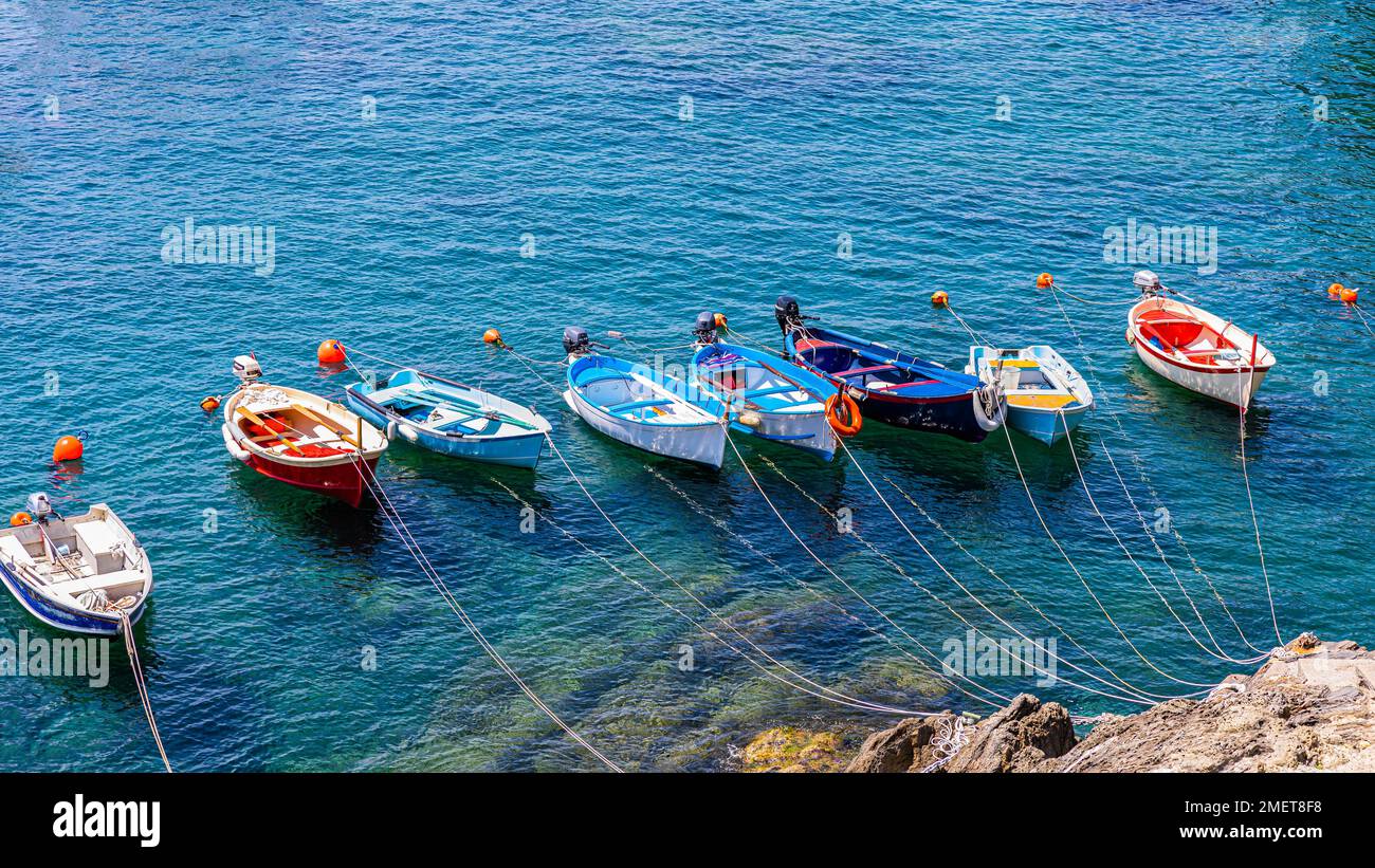 Colourful fishing boats attached to the rock lie in the turquoise water ...