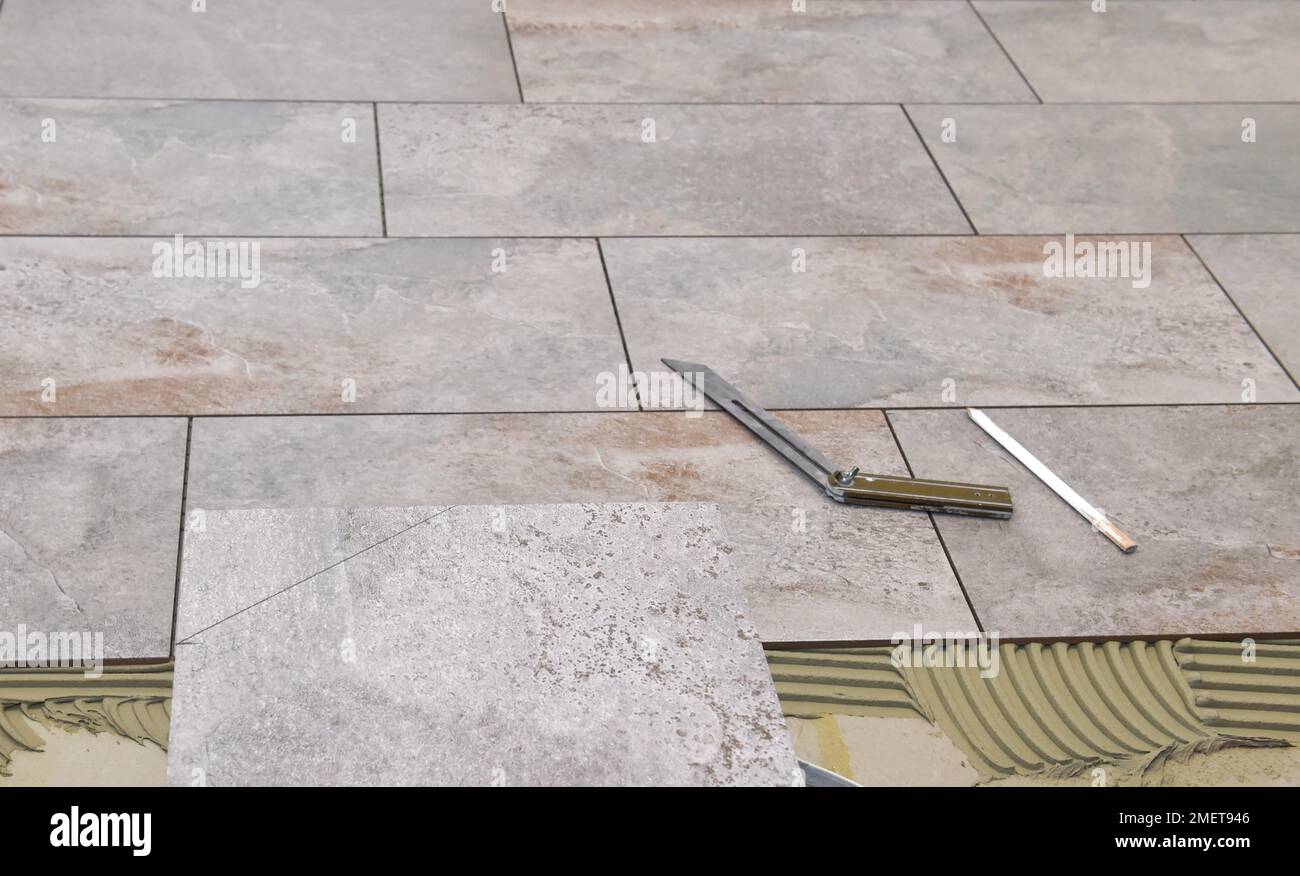 Tiler has applied tile adhesive and is sticking on new tiles, Hesse ...