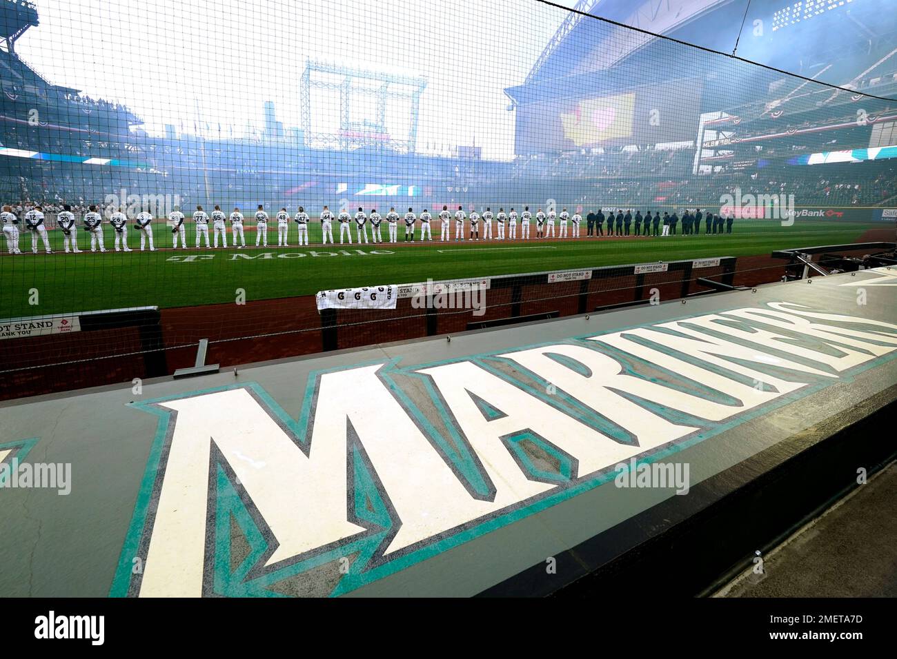 Seattle Mariners players and coaches stand along the first base line ...