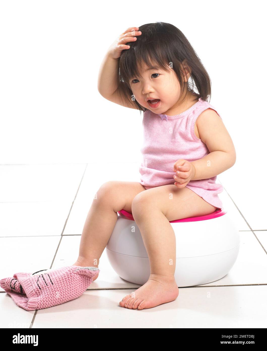 Girl wearing pink vest, pink wooly hat on foot, sitting on white potty, 20 months Stock Photo ...