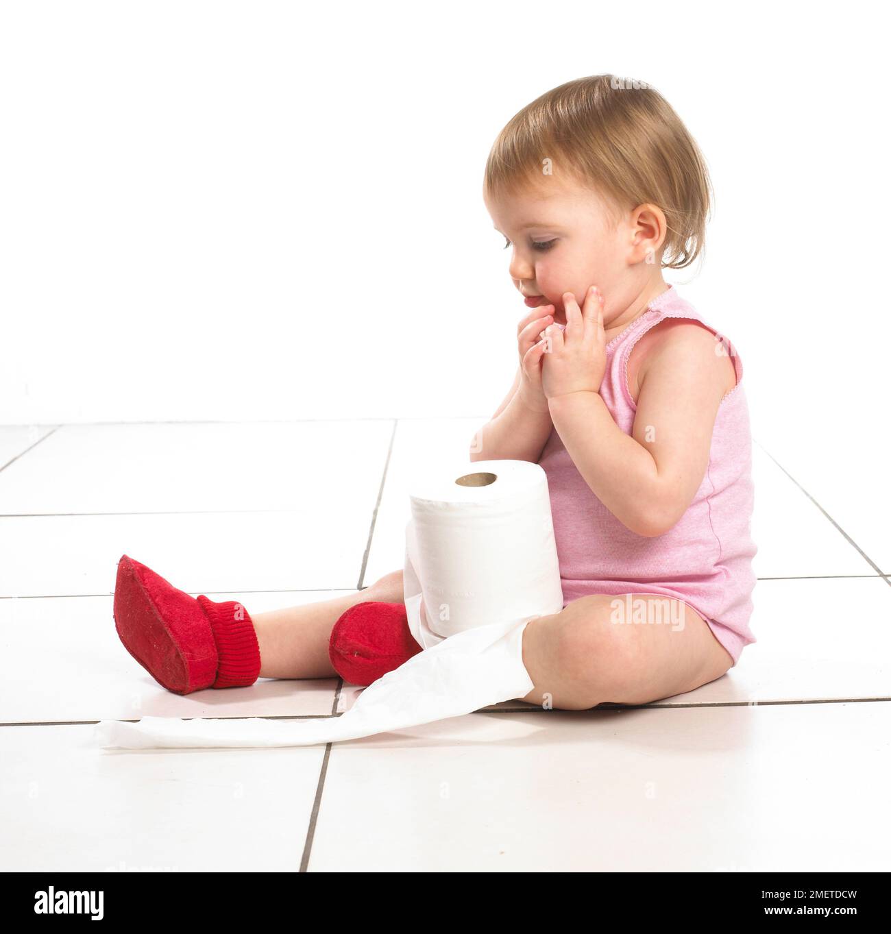 Girl Wearing Red Socks And Pink Top Sitting With Rolls Of Toilet Paper