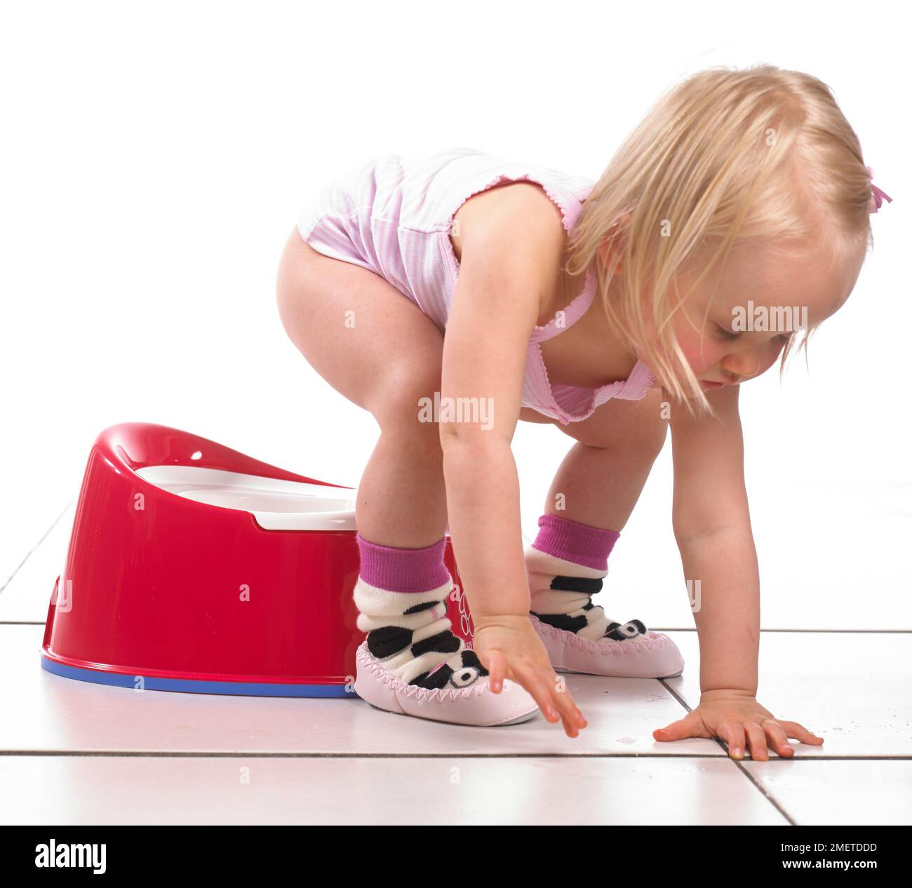 Girl wearing vest and slippers standing up from a potty, 20 months Stock Photo - Alamy