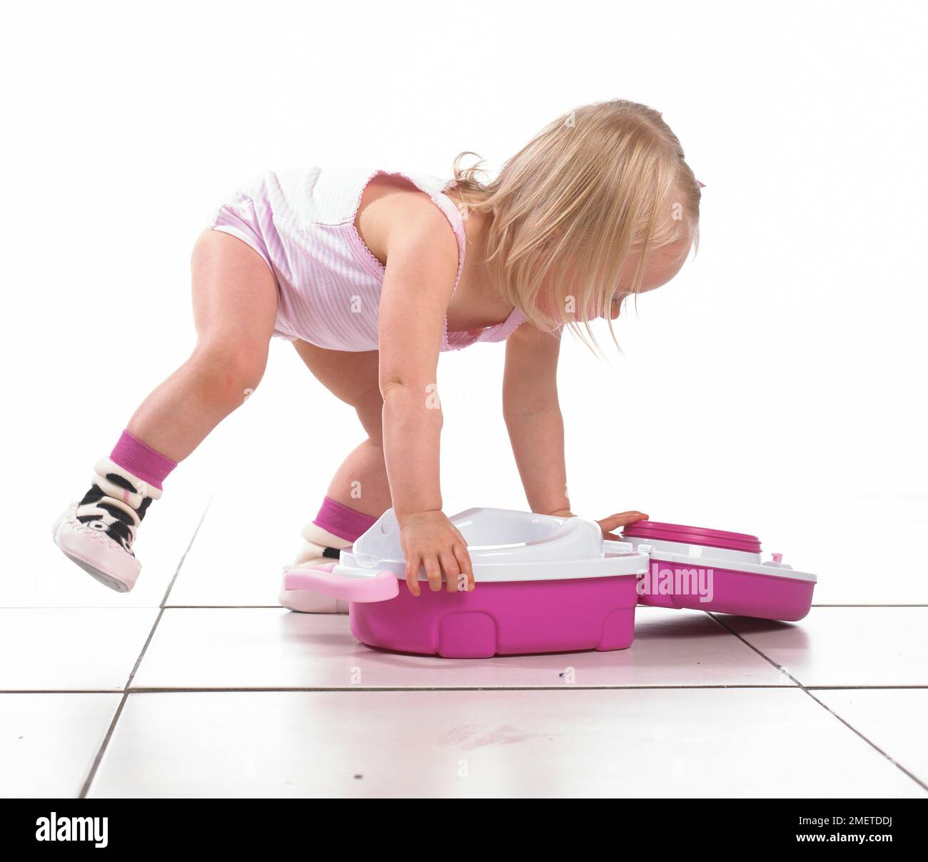 Girl wearing vest, pants and slippers playing with an open portable potty, 20 months Stock Photo ...