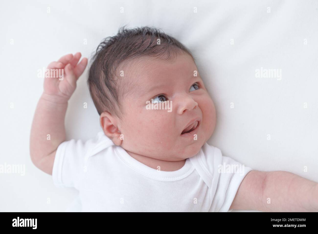 Baby girl lying on back with her head turned to side, looking up Stock ...