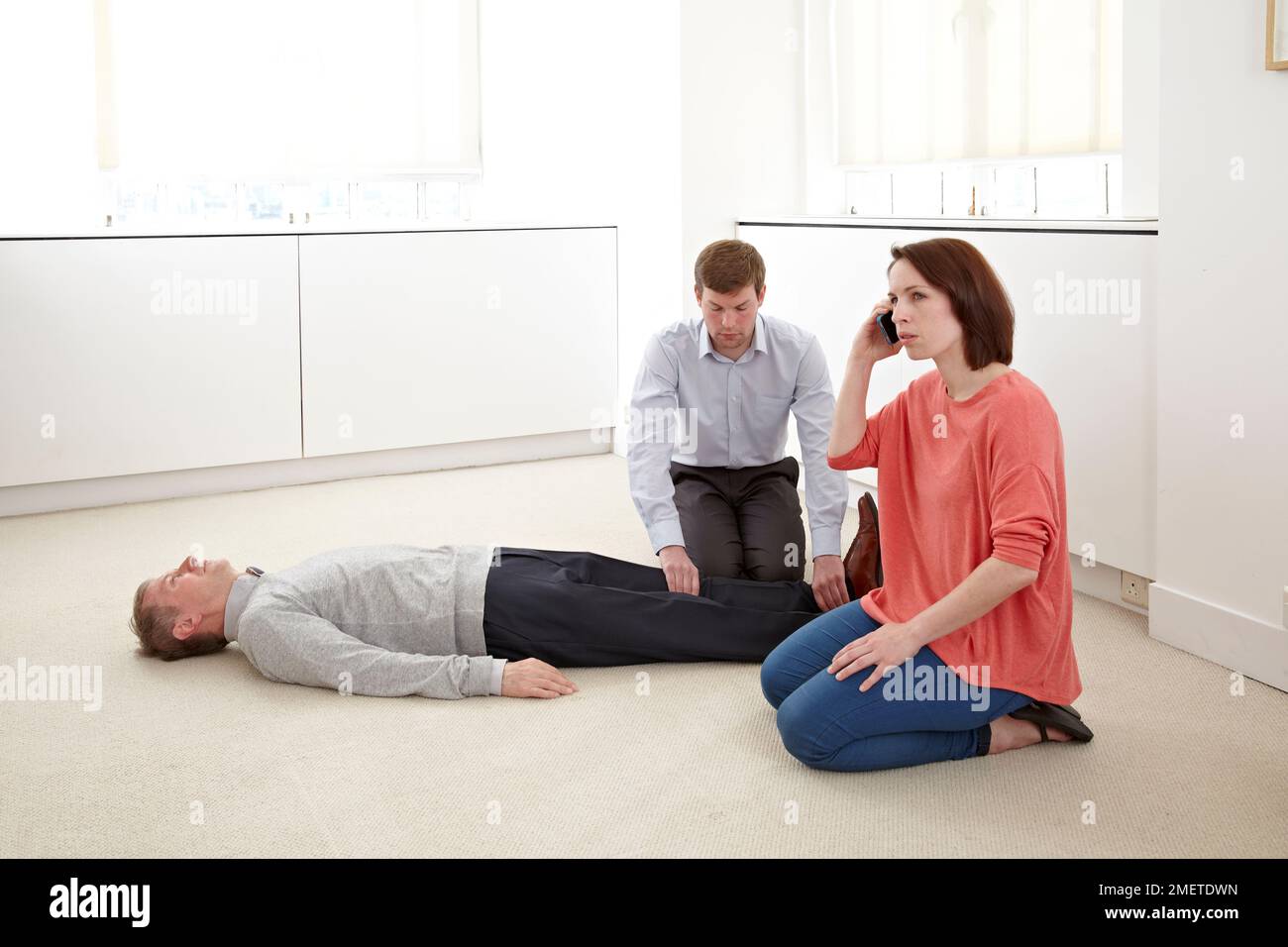 First aid treatment of lower leg injury, helping casualty to lie down ...