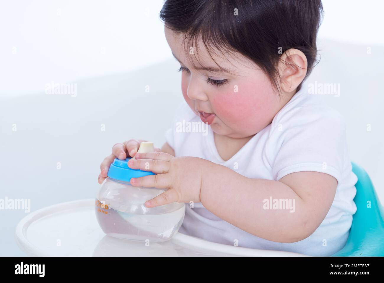 Baby girl (40 weeks) holding plastic drinking cup filled with water ...