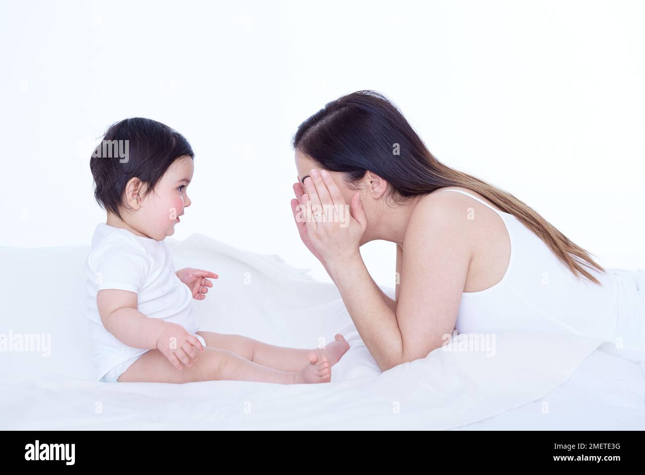 Baby girl (40 weeks) and mother facing each other, mother is covering ...