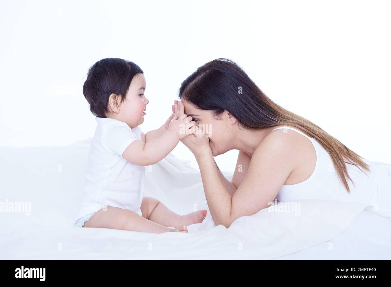 Baby girl (40 weeks) grasping hands of her mother who is covering her ...