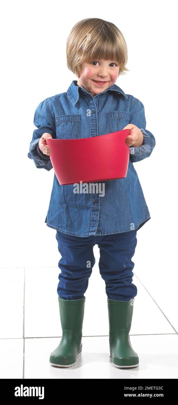 Boy standing holding a red bucket, 3 years Stock Photo - Alamy