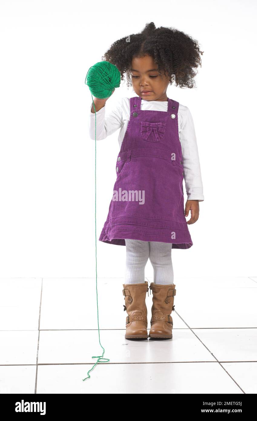 Girl standing holding ball of wool, 3 years Stock Photo - Alamy