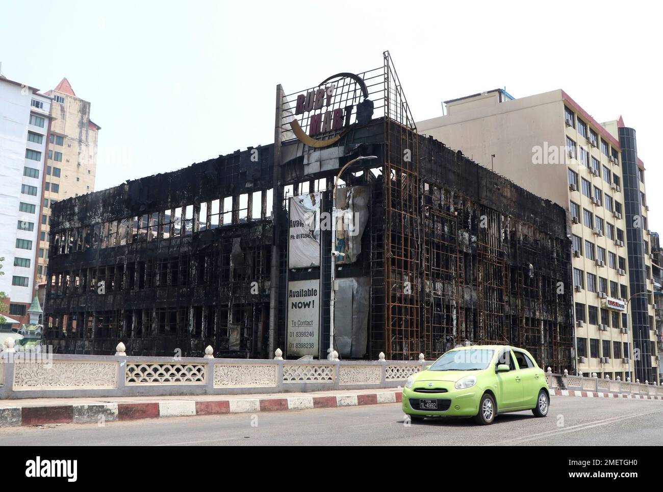 A car passes by the burned military-controlled Ruby Mart after a fire ...