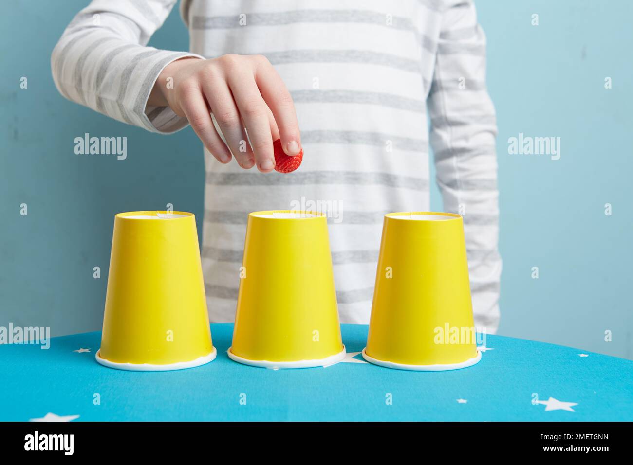 Child performing cups and balls trick Stock Photo - Alamy