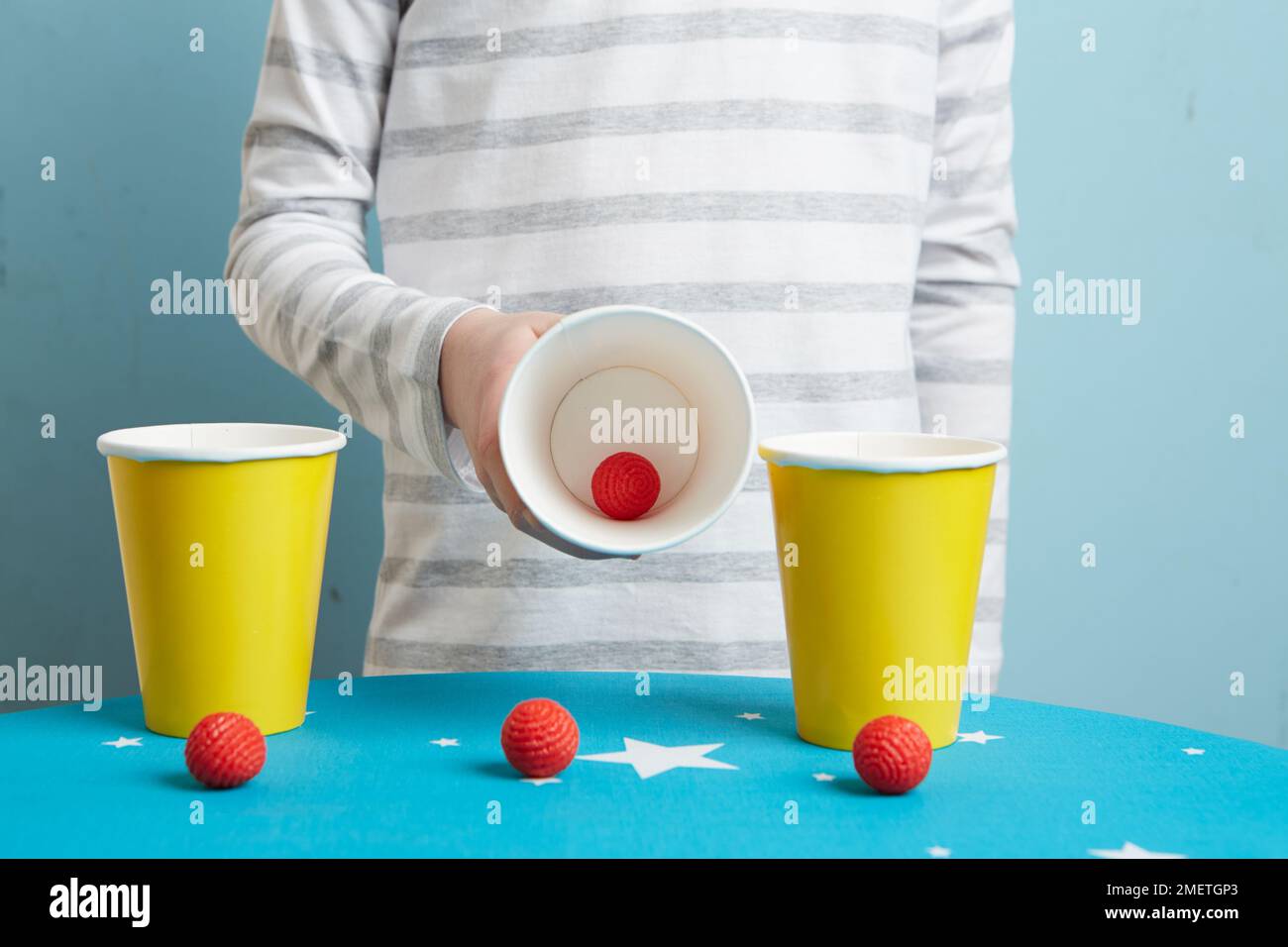 Child performing cups and balls trick Stock Photo - Alamy