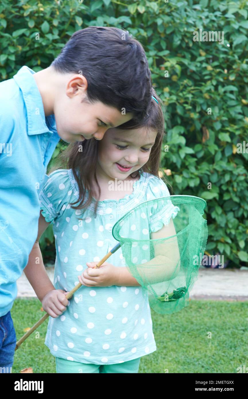 Boy and girl looking at frog in fishing net Stock Photo - Alamy