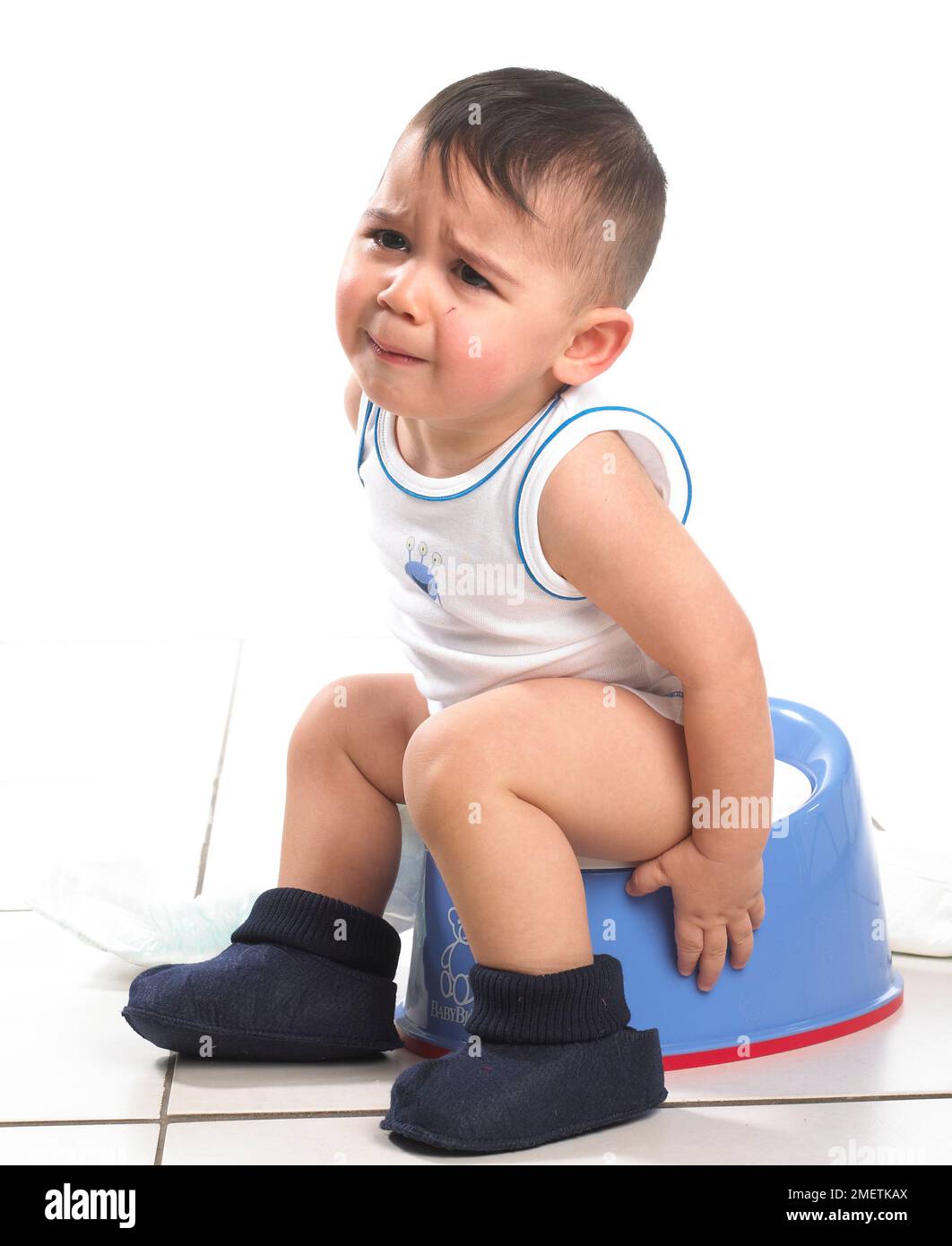 Boy wearing vest and slippers sitting on blue potty, 15 months Stock ...