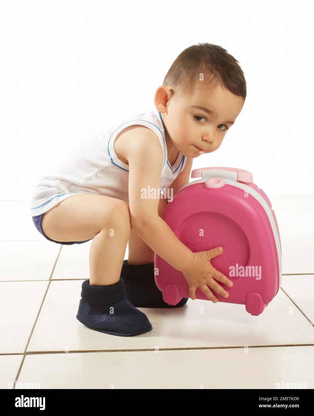 Boy wearing vest and pants picking up travel potty, 15 months Stock ...