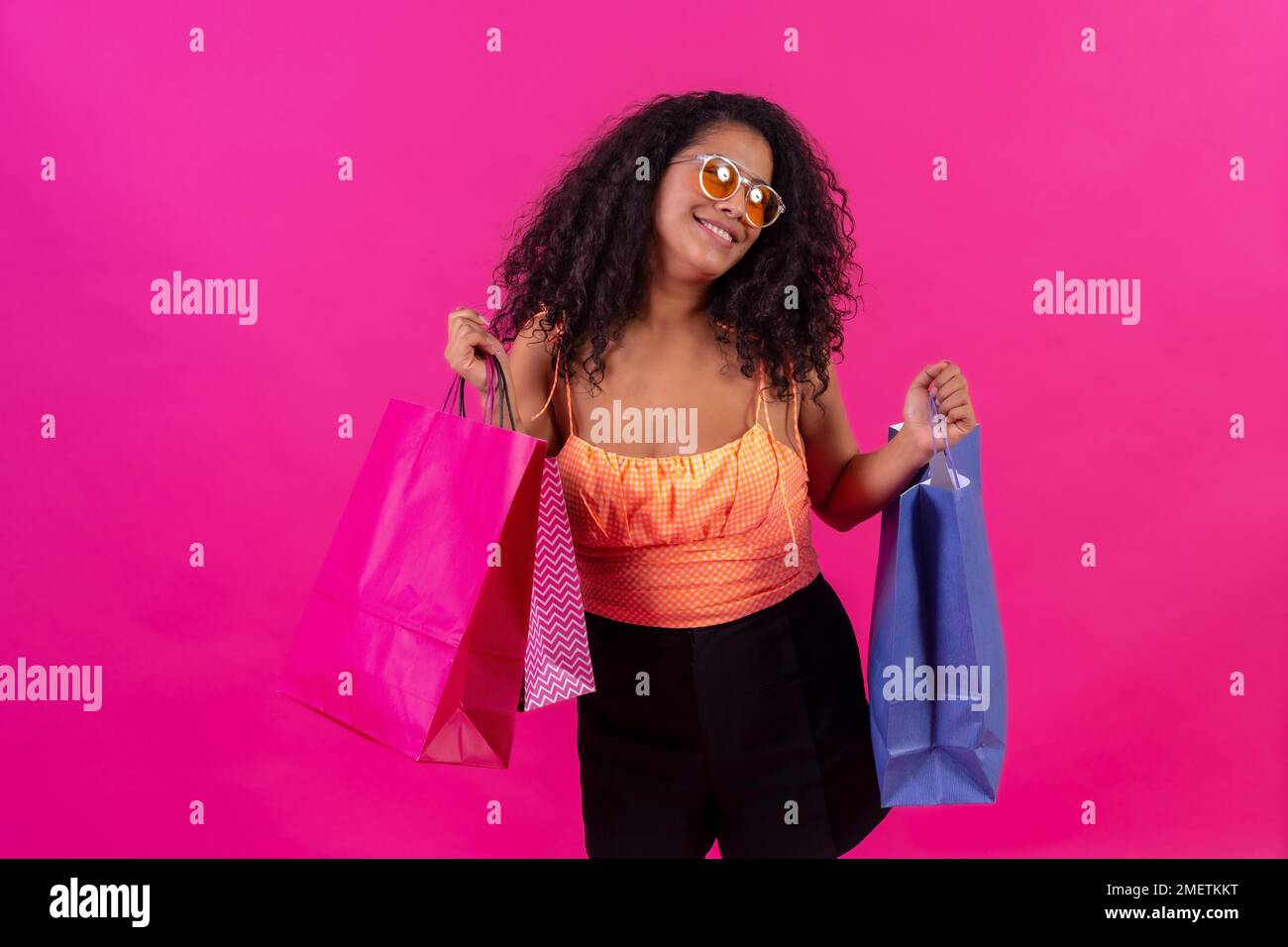 Curly-haired woman on a pink background, shopping concept with the bags ...