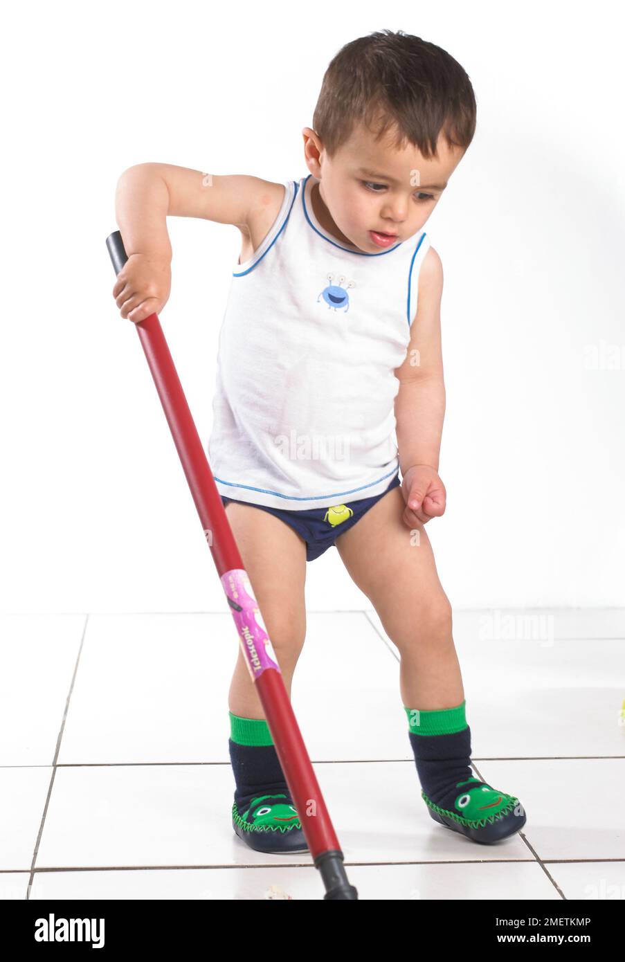 Boy wearing vest and slippers playing with a mop, 15 months Stock Photo ...