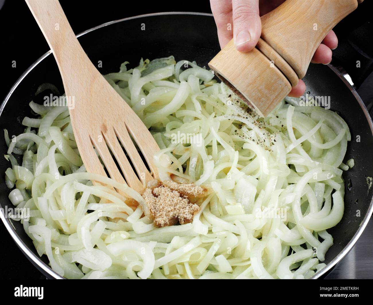 Making onion marmalade, adding seasoning (pepper, muscovado sugar) onto ...