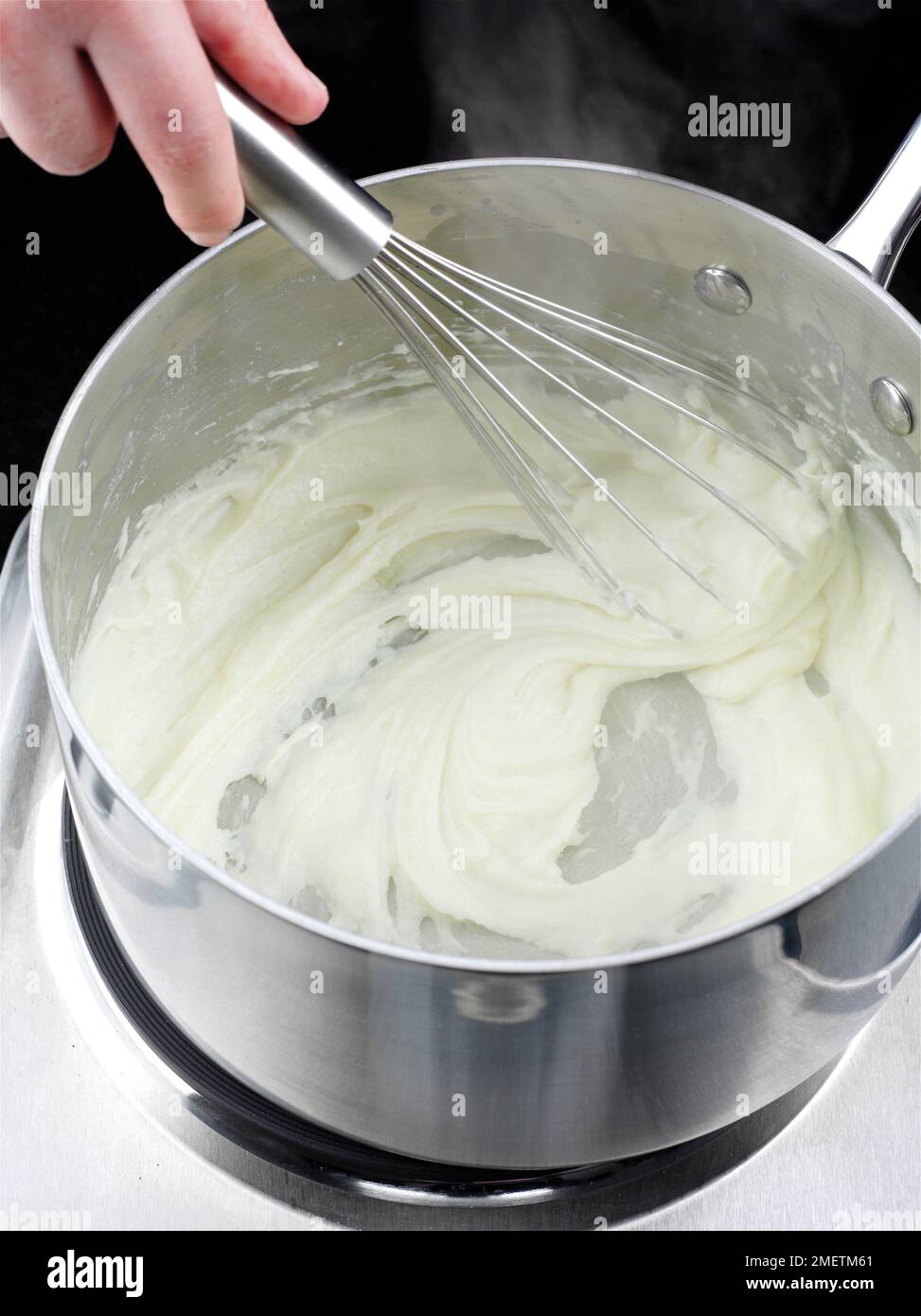 Making cheese souffles, whisking milk, flour and butter mixture in ...