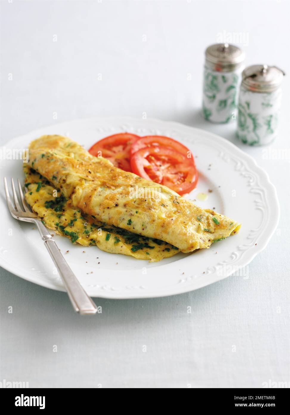 Classic French herbed omelette garnished with tomato slices, on plate ...