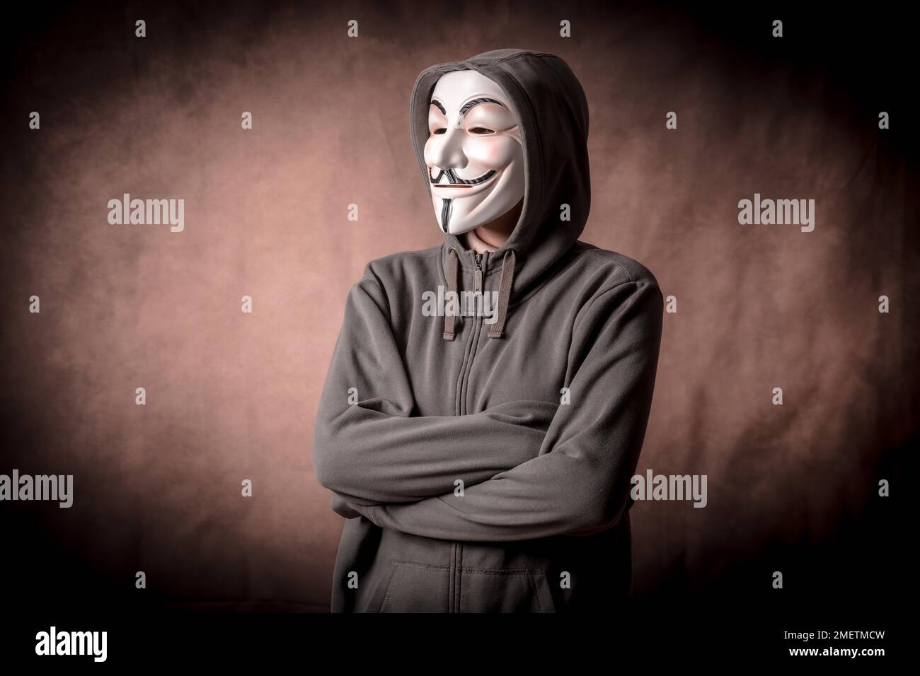 Man wearing anonymous mask with sweatshirt, looking left, studio shot ...