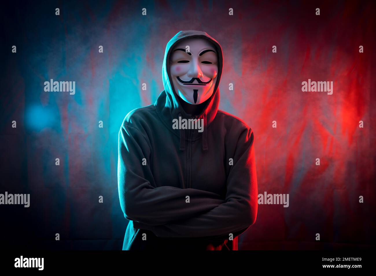 Hacker With Anonymous Mask With Arms Crossed Red And Blue Background