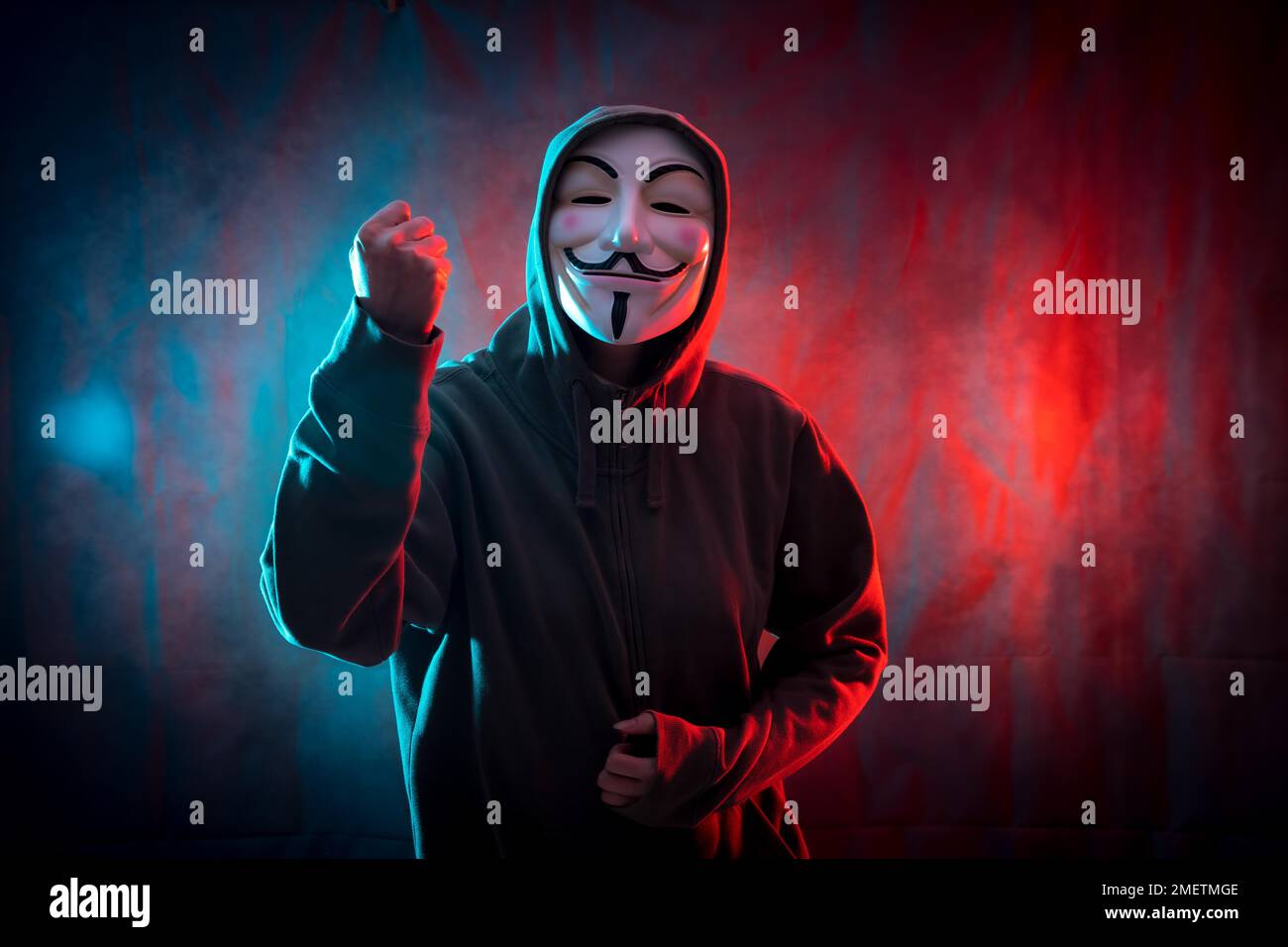 Hacker with anonymous mask with his fist raised in symbol of fight, red ...