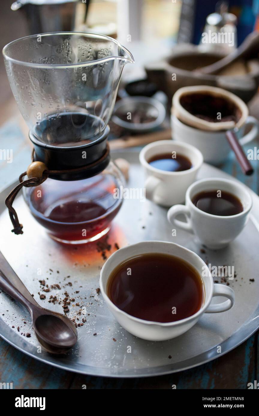 Caffe Touba, coffee draining through a cloth into glass jug, three cups ...