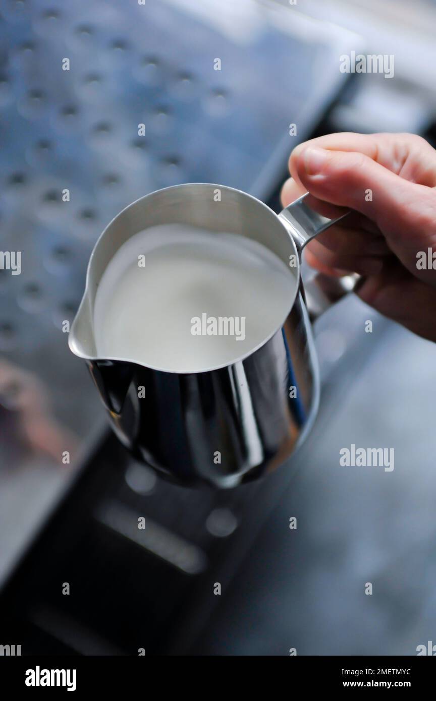 Holding pitcher of hot milk Stock Photo - Alamy