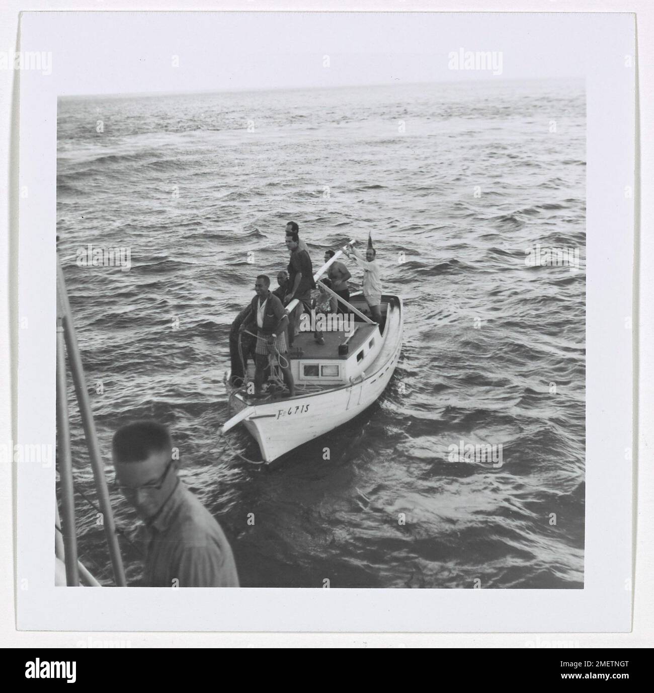 A photograph showing a small boat approaching a larger vessel, likely a ...