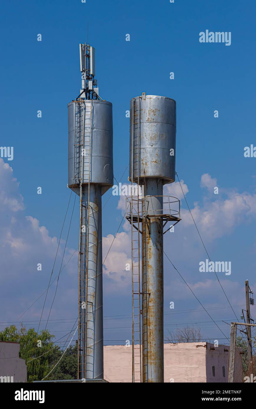 Two old style water towers surrounded by trees, with clear blue skies ...