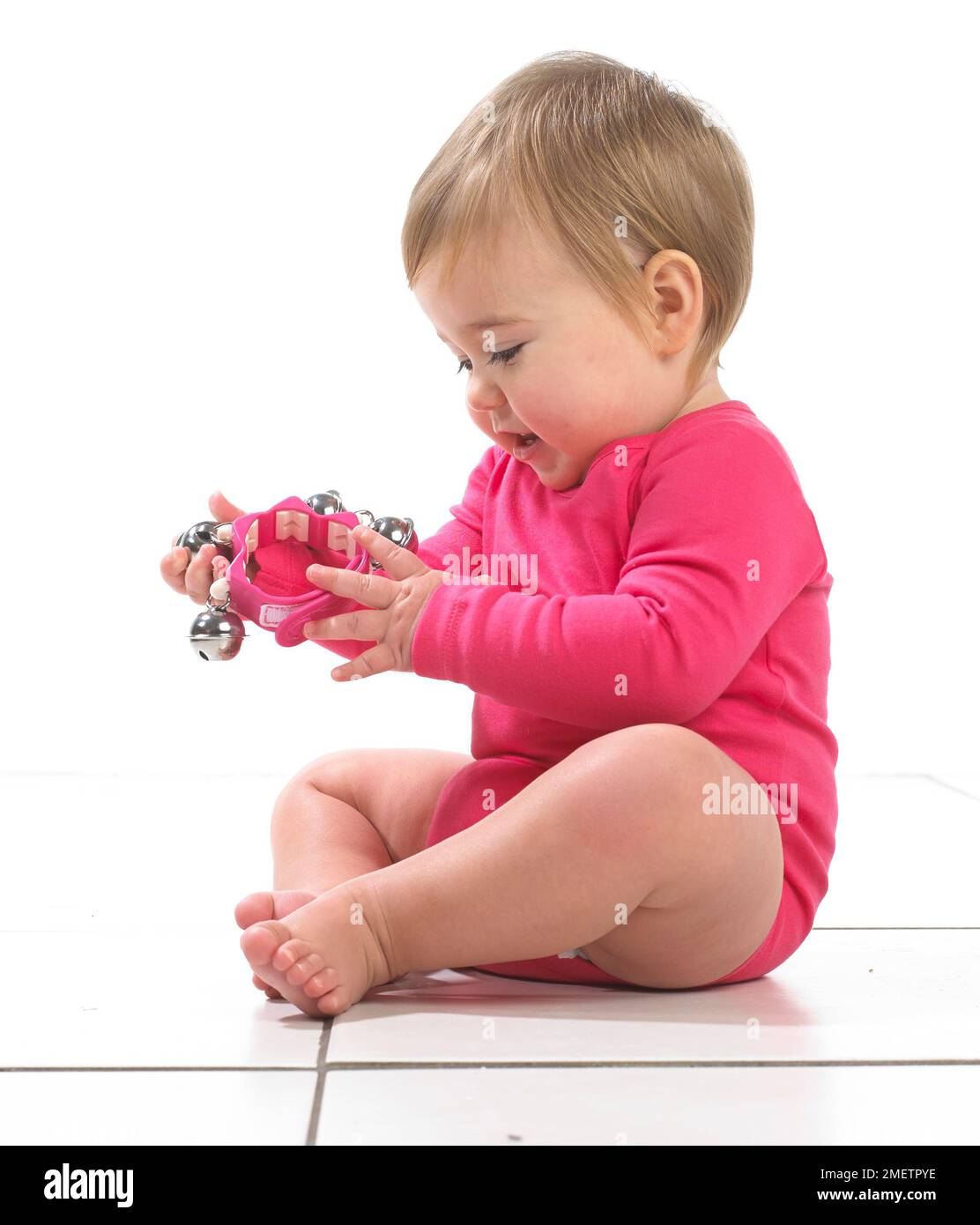Baby girl (12 months) sitting playing with jingle bells Stock Photo - Alamy