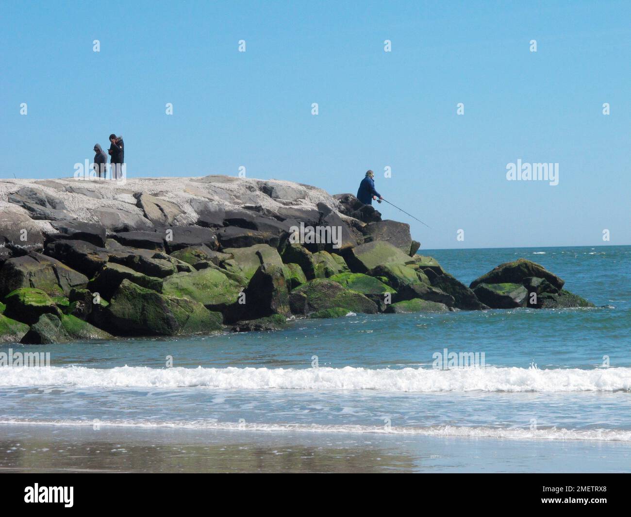 This March 30, 2021 photo shows people walking on and fishing from a ...
