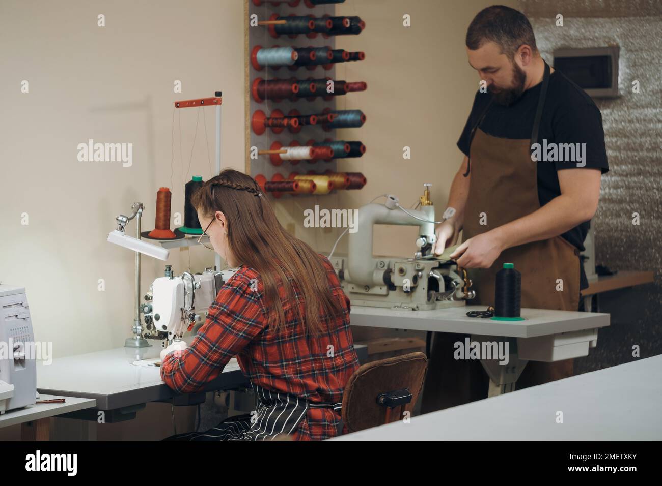 Workers sewing on professional sewing machine at workshop. Tailor ...