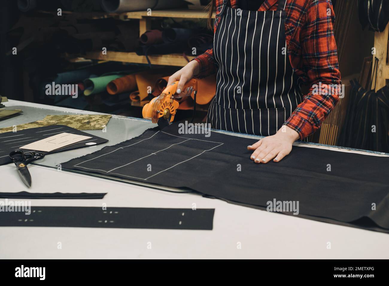 Seamstress at work. Dressmaker cutting fabric. Woman standing at table ...