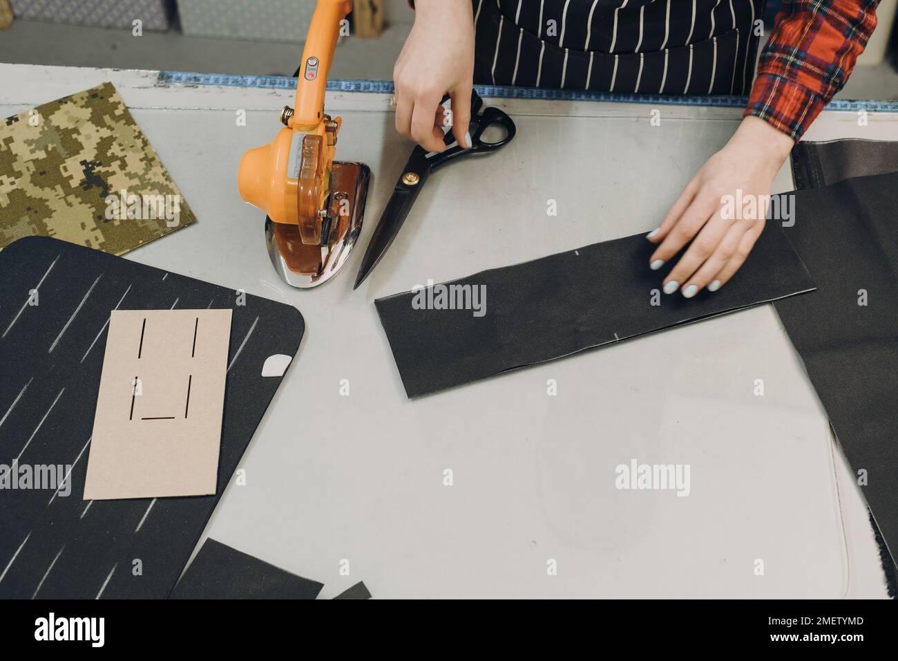 Seamstress at work. Dressmaker cutting fabric. Woman standing at table ...