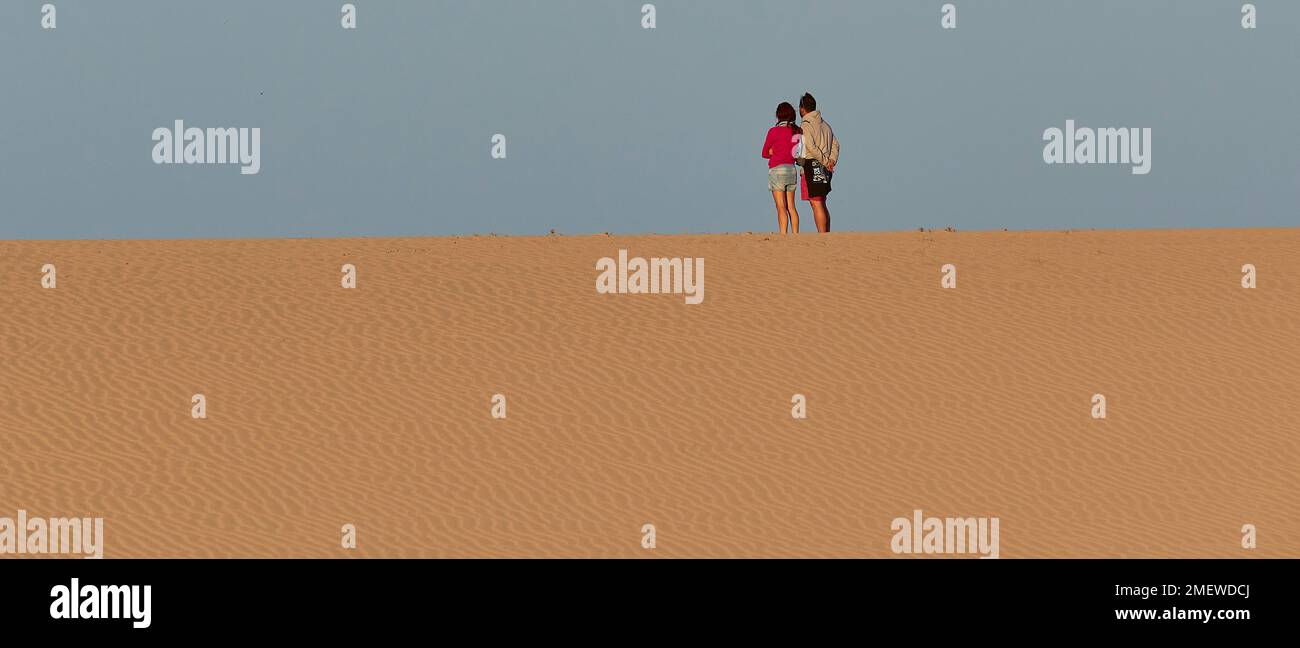 Dune, couple from behind on dune, close, cloudless blue sky, evening light, northeast coast ...