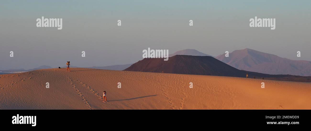 Ochre sand dune, hills, mountains, blue cloudless sky, people ...