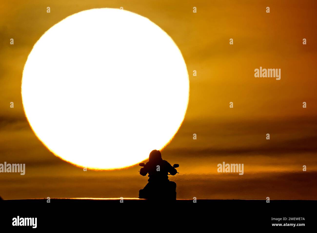 A motorcyclist is silhouetted against the setting sun, Sunday, March 28 ...